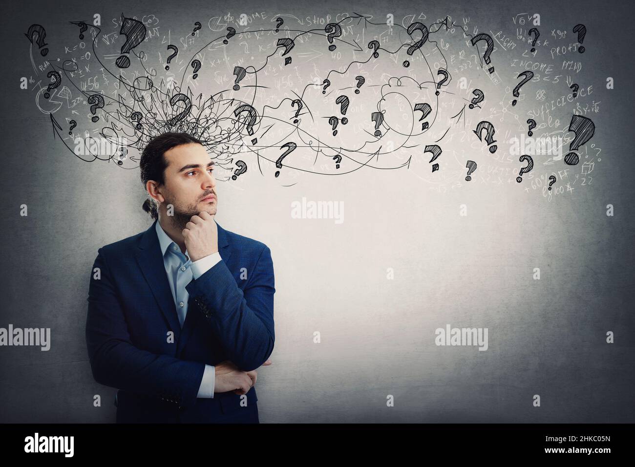 Thoughtful businessman keeps hand under chin, looking away pensive ...