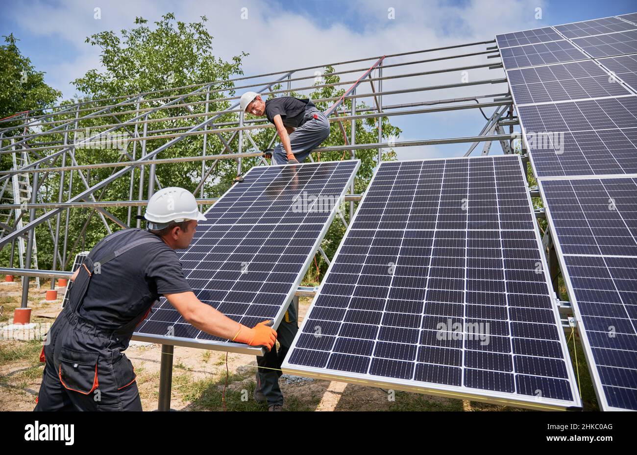 Male workers building photovoltaic solar panel system outdoors. Men ...
