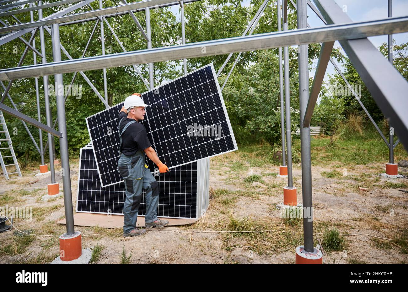 Full length of man solar installer carrying solar module while ...