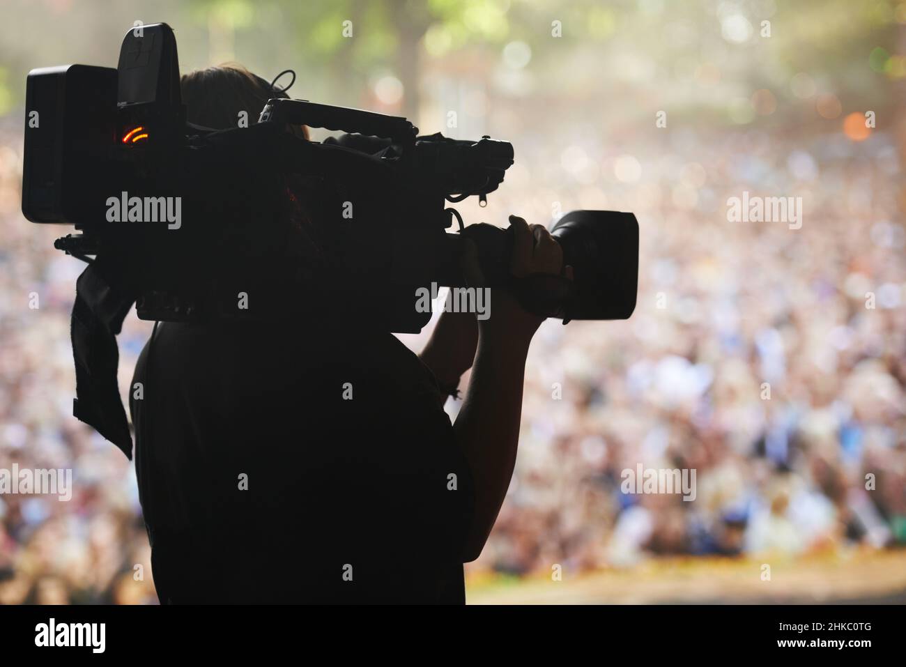 Capturing the excitement. A silhouette of a cameraman filming an event ...