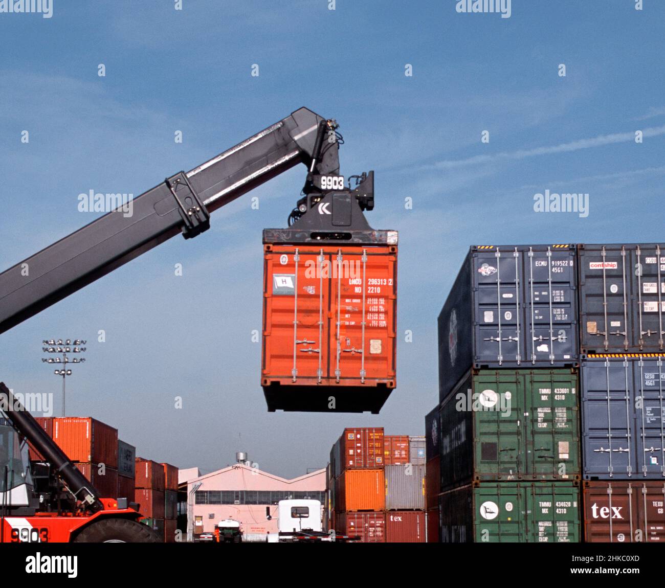 Forklift crane stacking cargo container at a commercial dock. Stacking ...