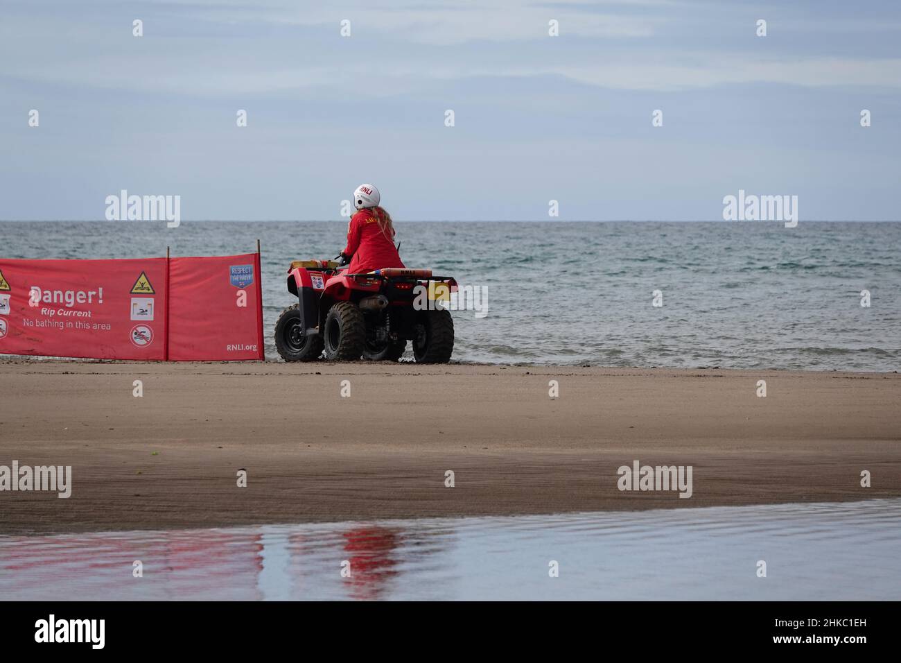Lifeguard riding a RNLI quad bike on a beach in the UK Stock Photo - Alamy