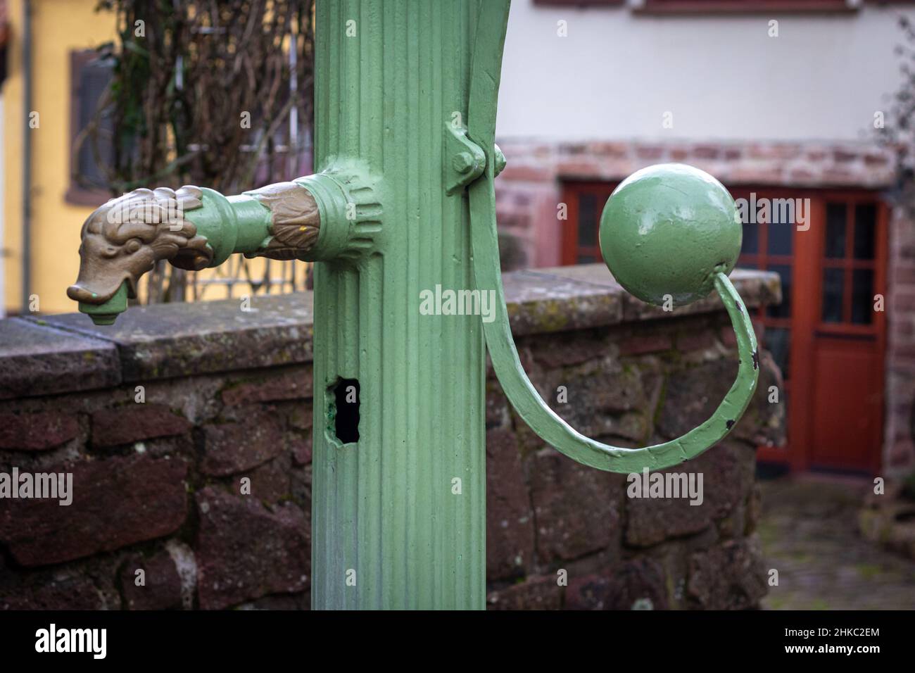 old decorated manual water pump made of green painted cast iron on a ...