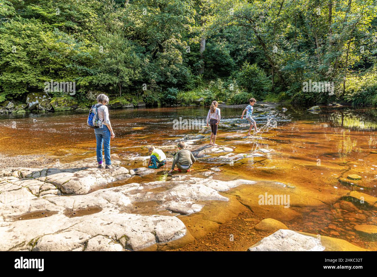 Children playing happily in the peaty waters of the River Allen at ...