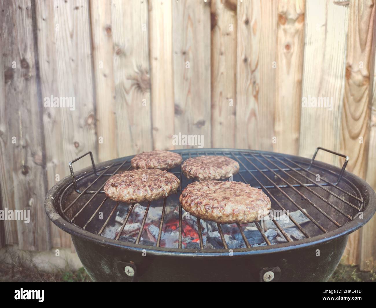 Close up photos of big delicious hamburger on grid barbecue at backyard ...