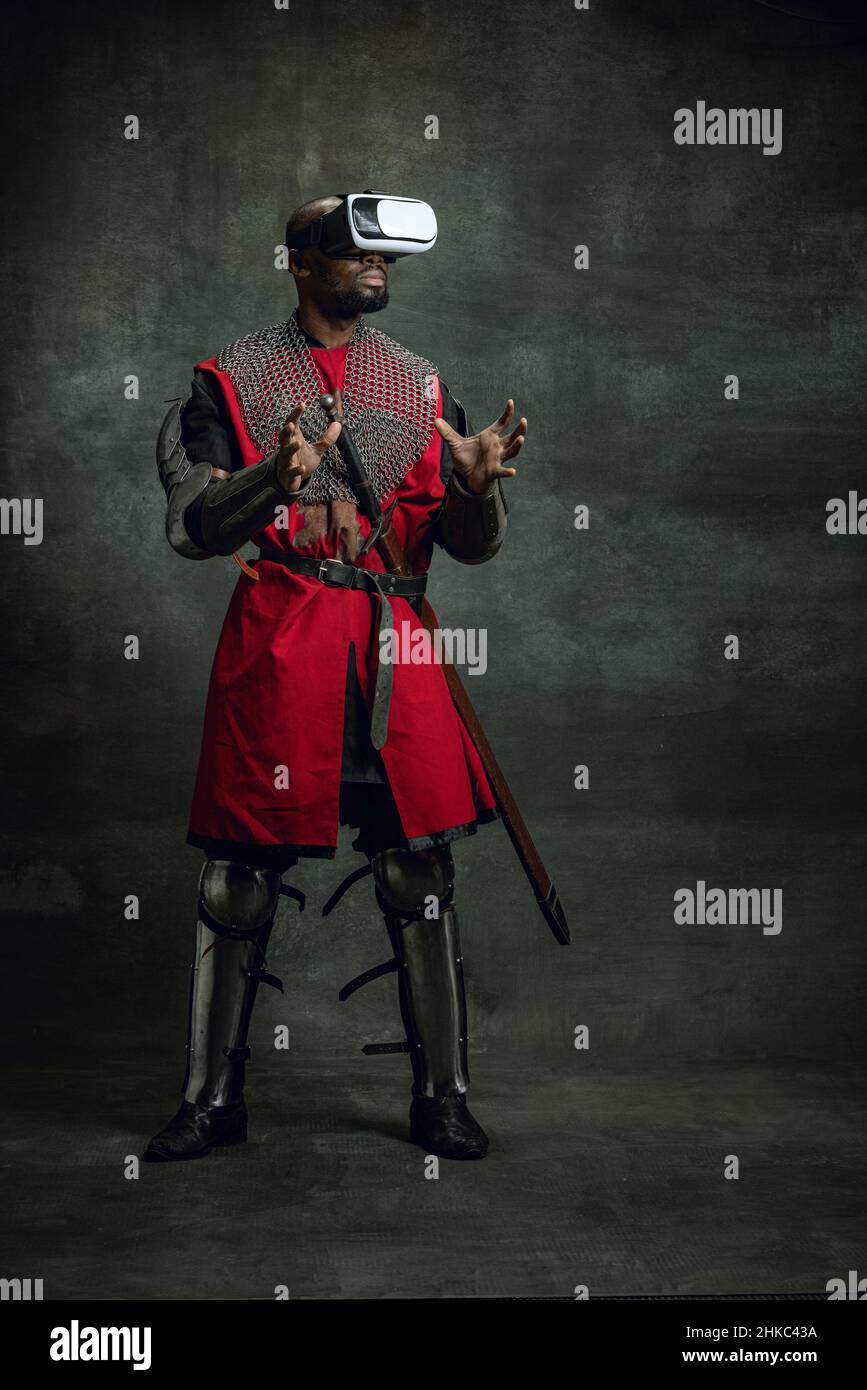 Modern gadgets. One dark skinned man, medieval warrior or knight using ...