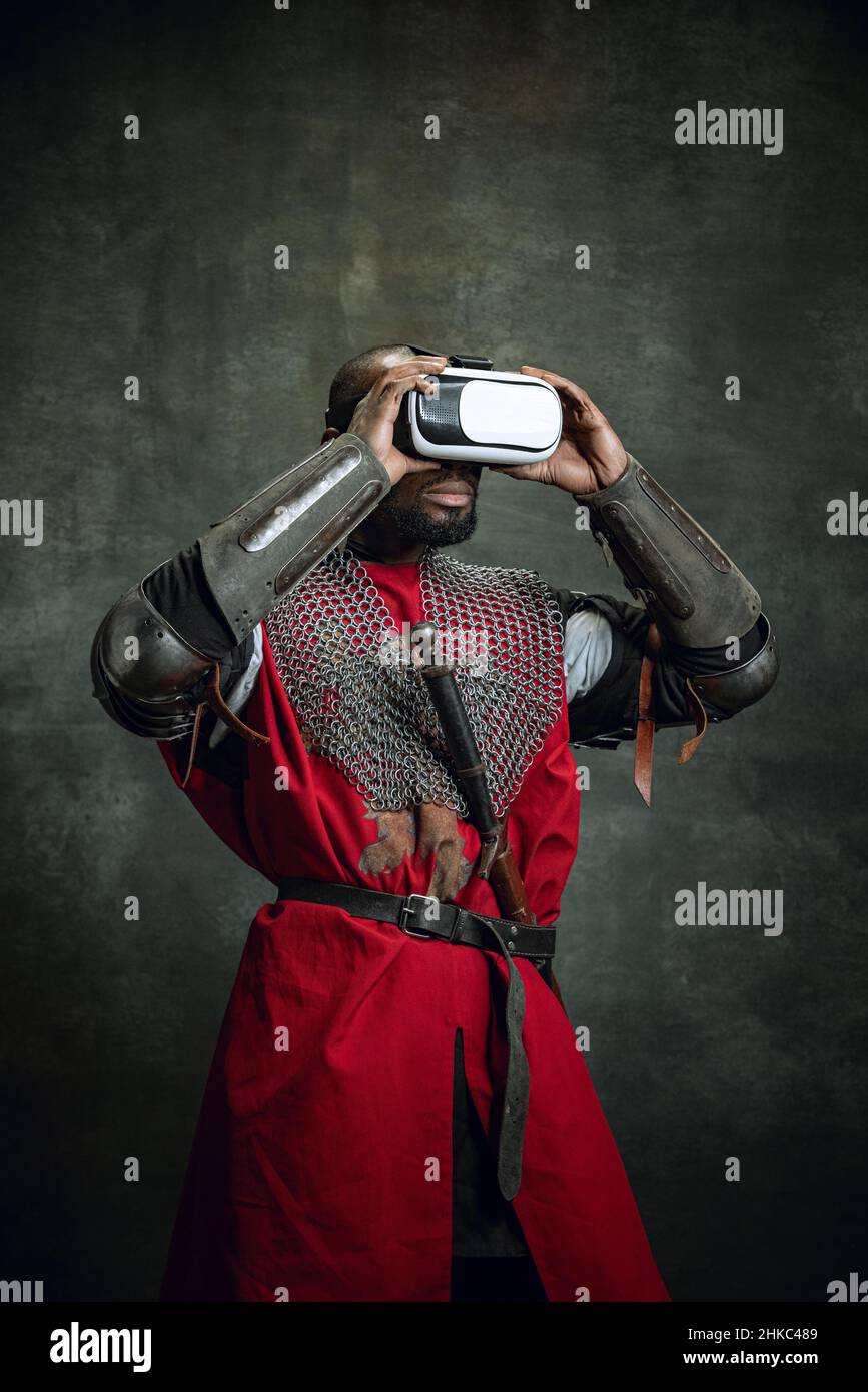 Modern gadgets. One dark skinned man, medieval warrior or knight using ...