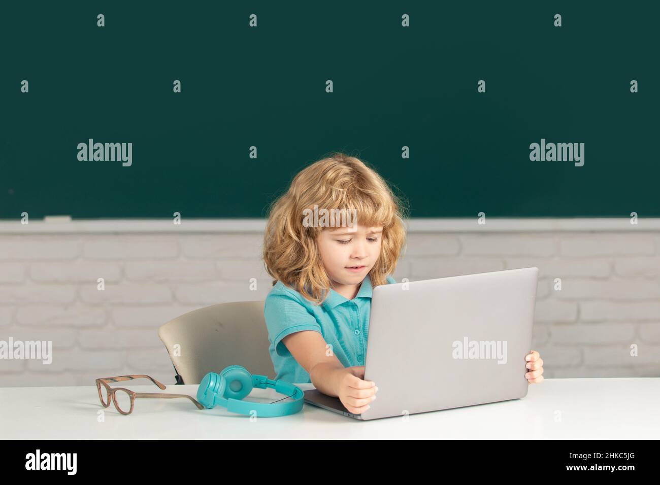 Kid boy learning lesson at school, making homework and using notebook ...