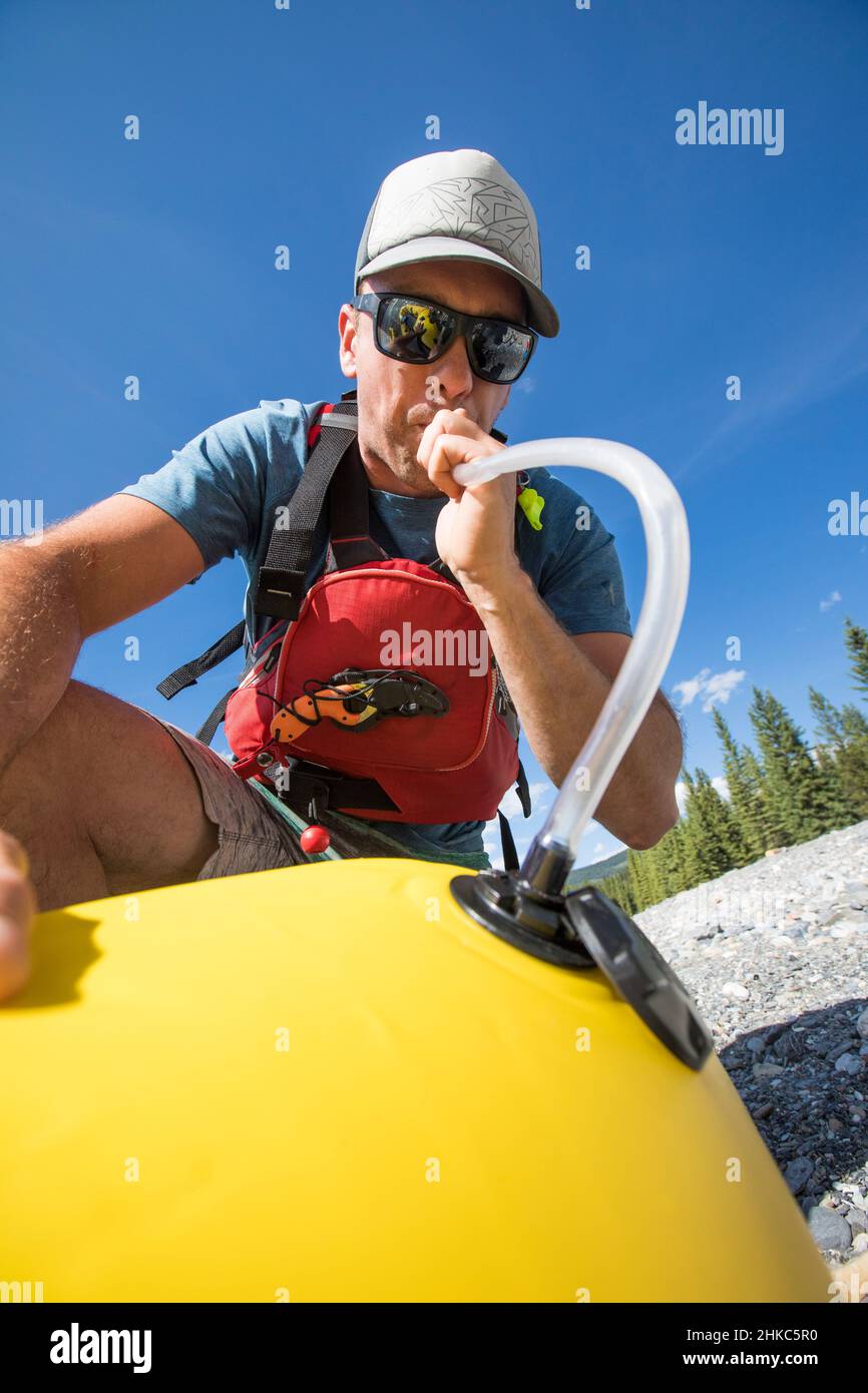 Man uses straw tube and lungs to inflate packraft Stock Photo - Alamy