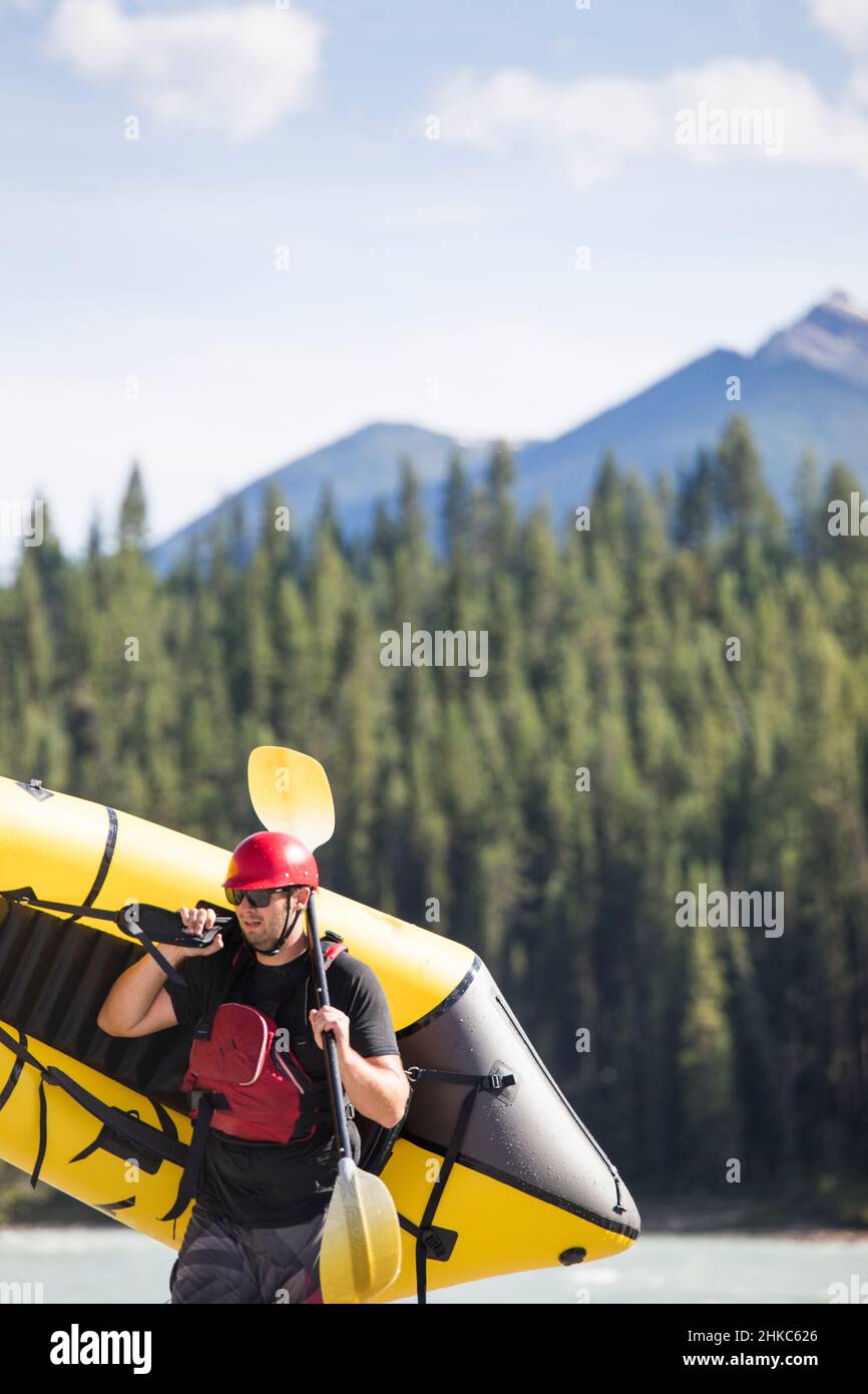 Scenic image of man carrying yellow raft (packraft) in wilderness Stock ...
