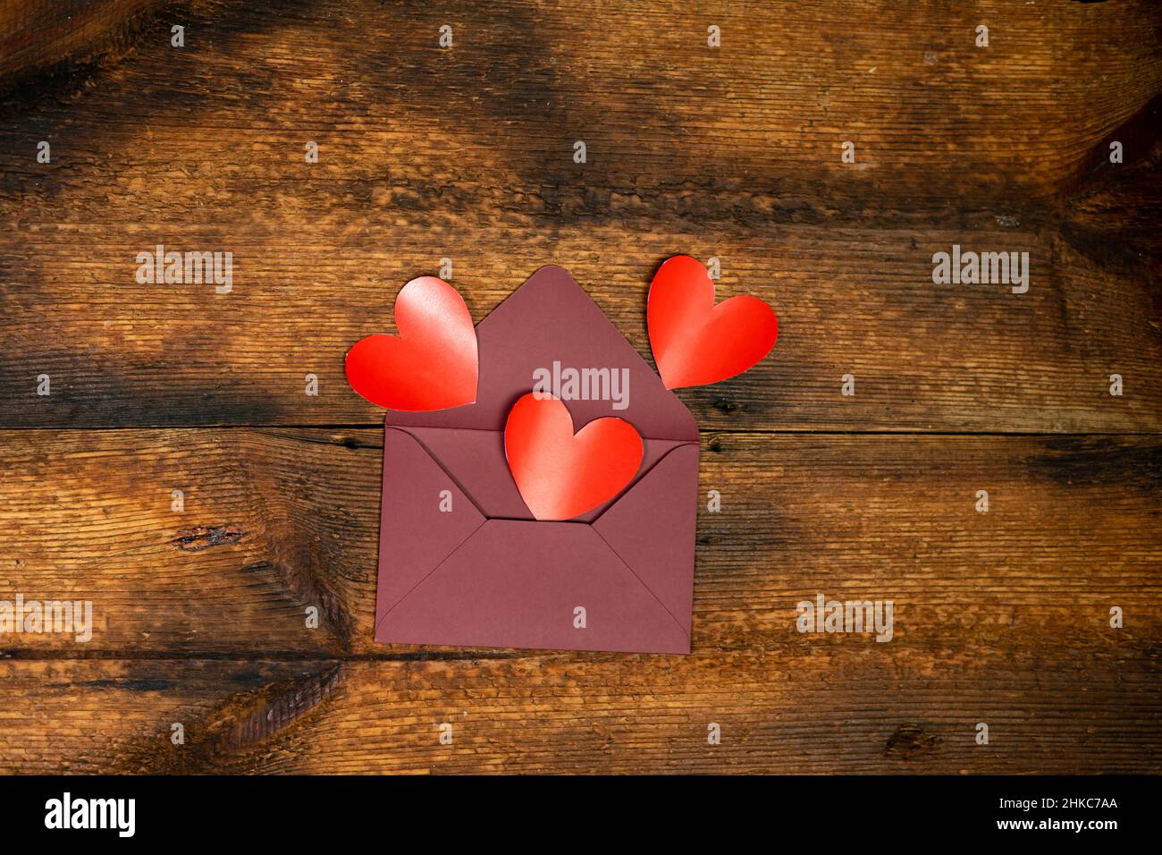 Open envelope with red hearts. Dark wooden background. Love ...