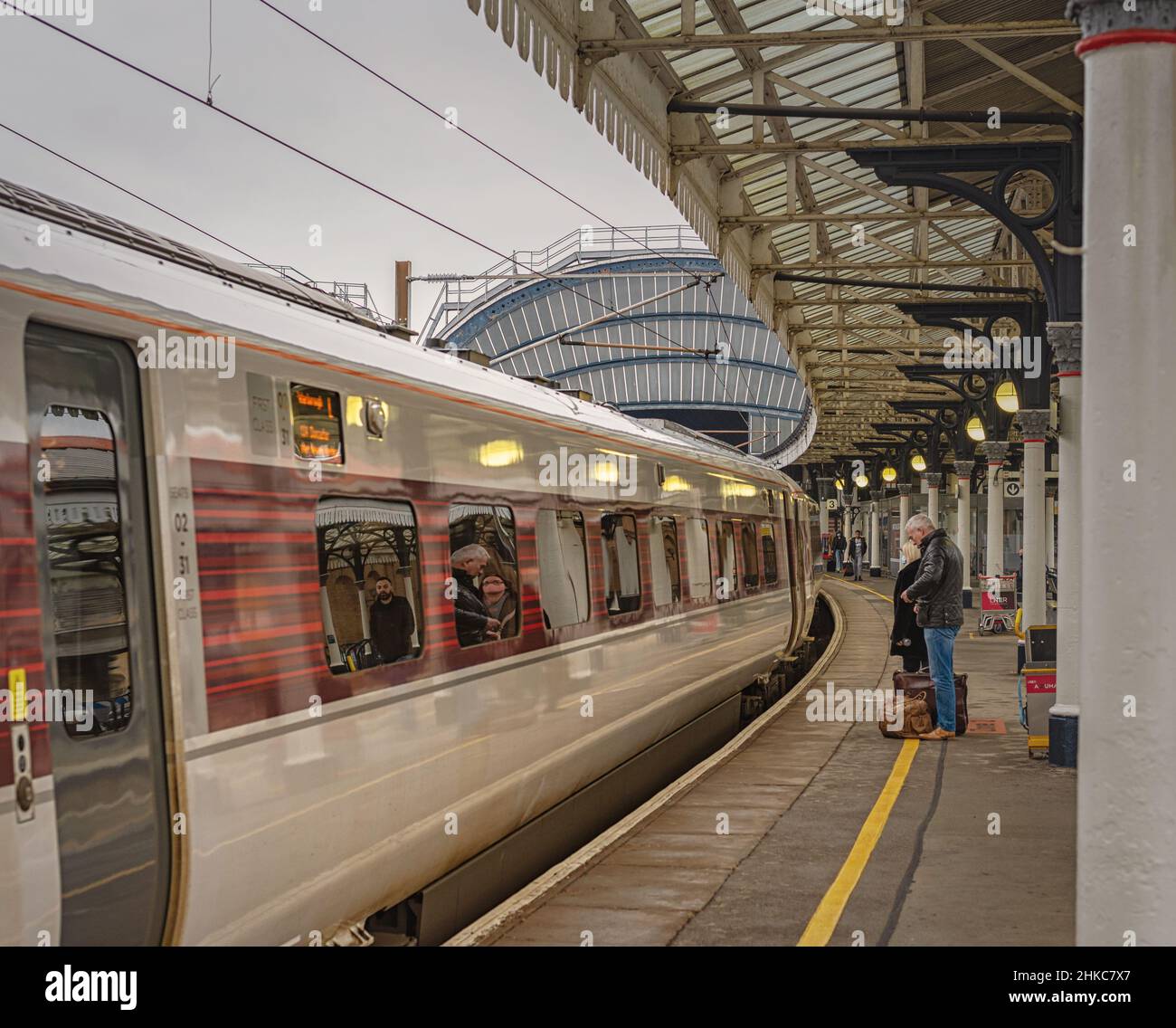 Railway station platform with passengers waiting for a train. Overhead ...