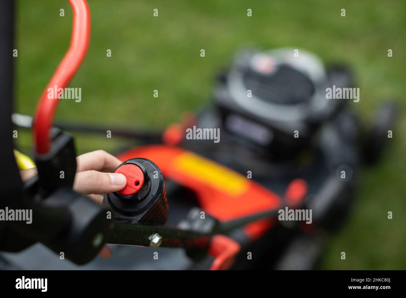Pushes the start button on a lawn mower to cut grass Stock Photo - Alamy