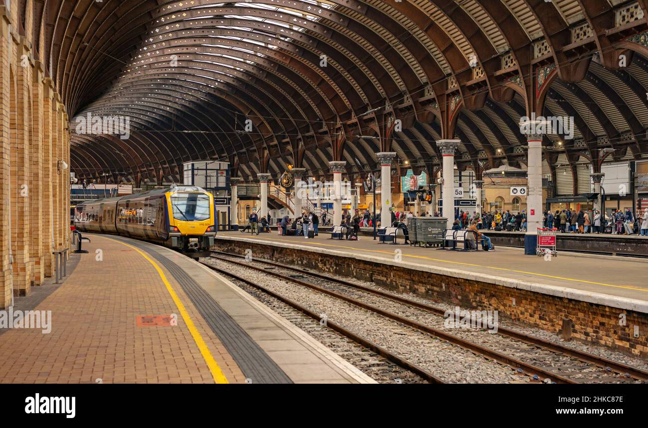 A railway station with a train waiting to depart. A metal and glass ...