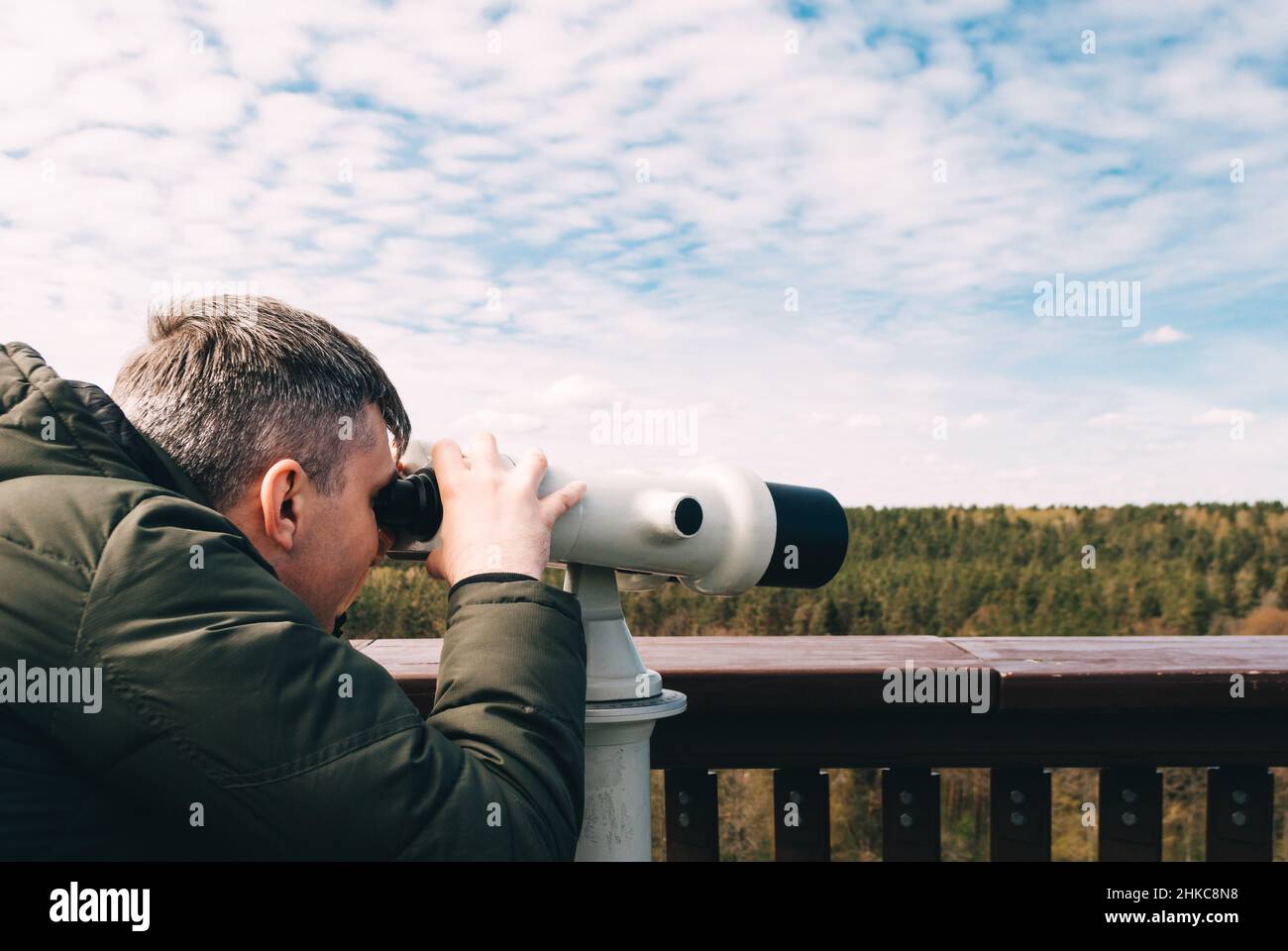 Man looks into the distance from observation deck, using Tower viewer ...
