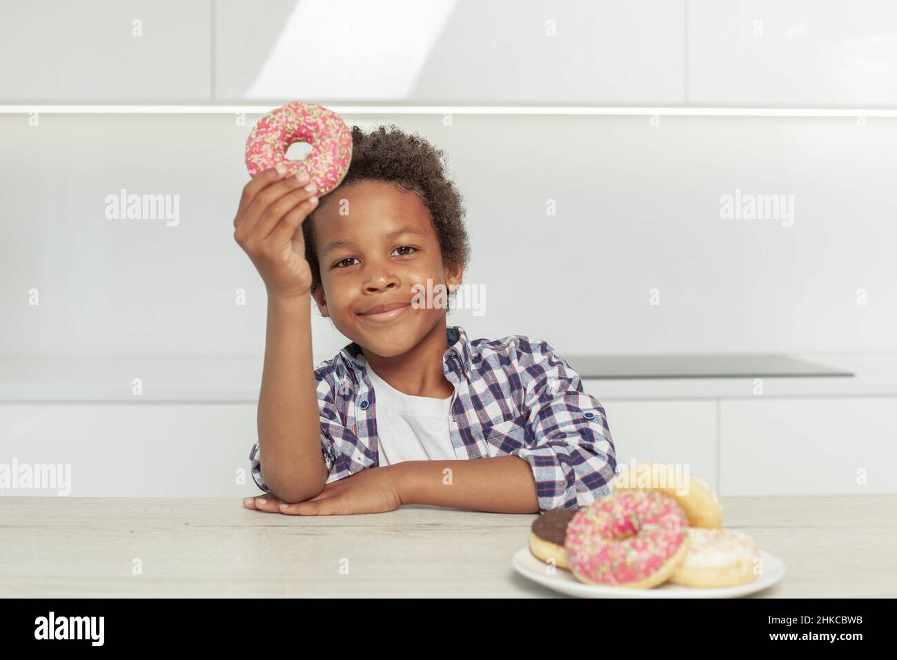 Smiling little boy showing donuts on white background Stock Photo - Alamy