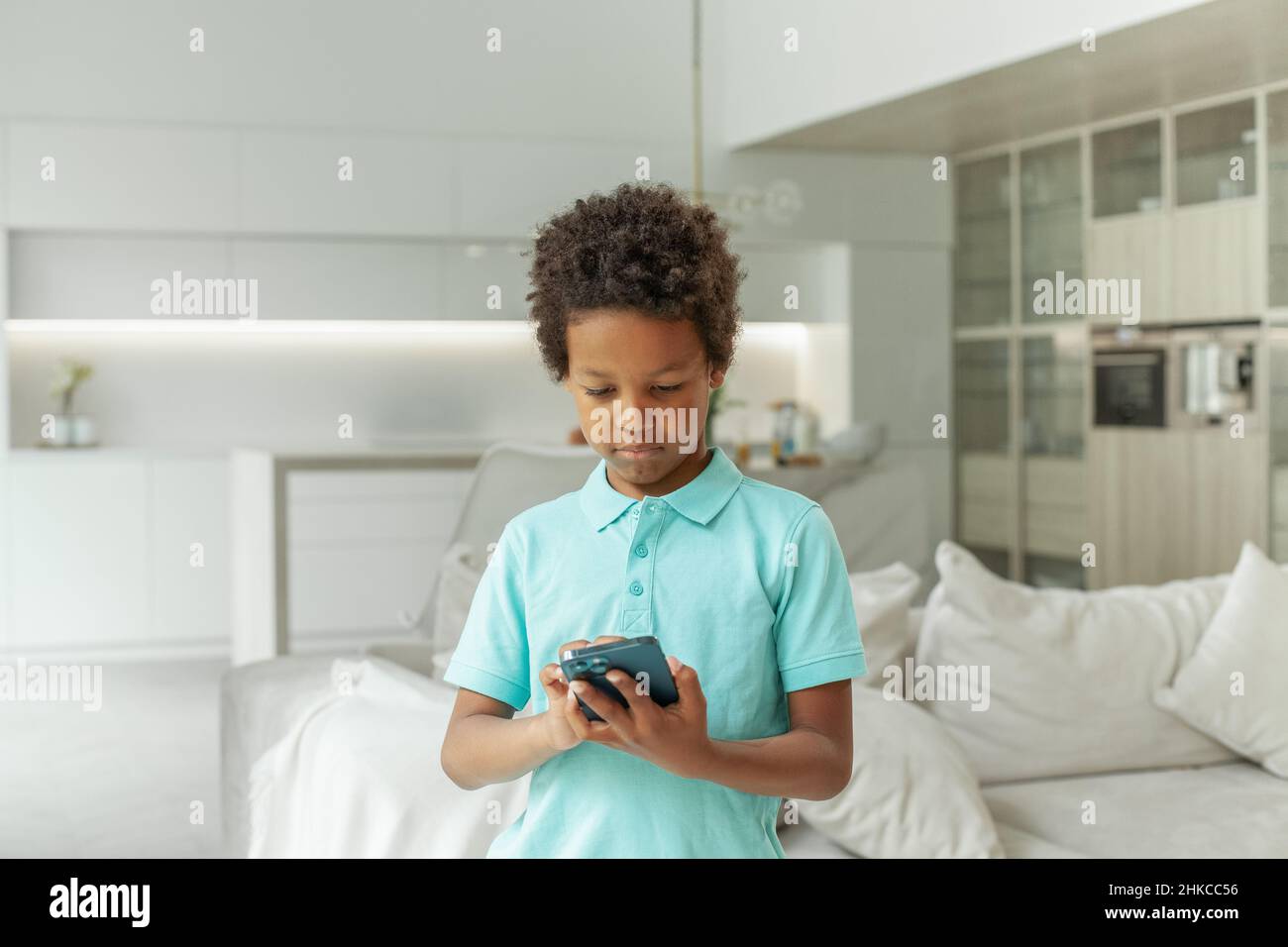 Serious kid boy with phone at home Stock Photo - Alamy