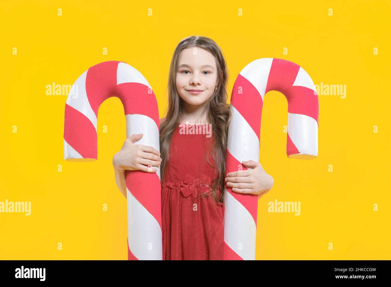 Portrait of a beautiful little girl holding two huge candy in her hands ...