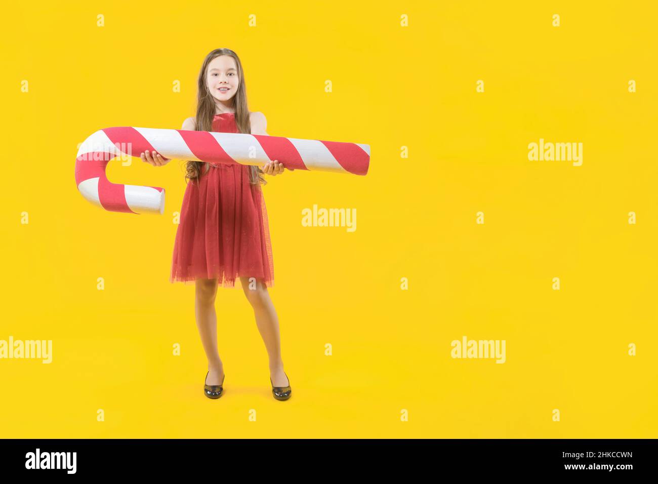 A beautiful little girl holds a huge candy horizontally in her hands on ...