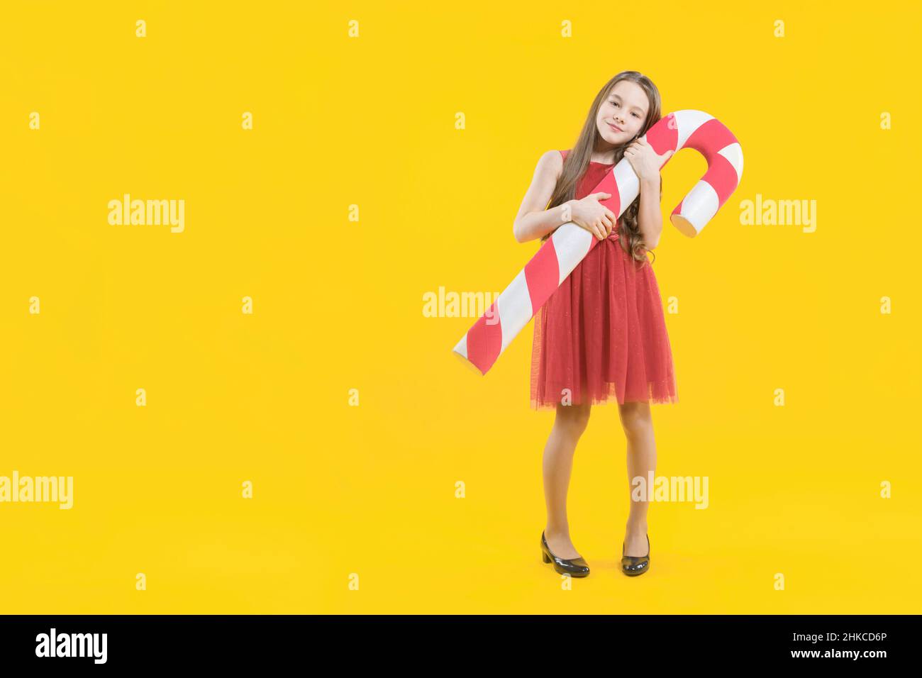 A beautiful little girl holding a huge candy in her hands with her head ...