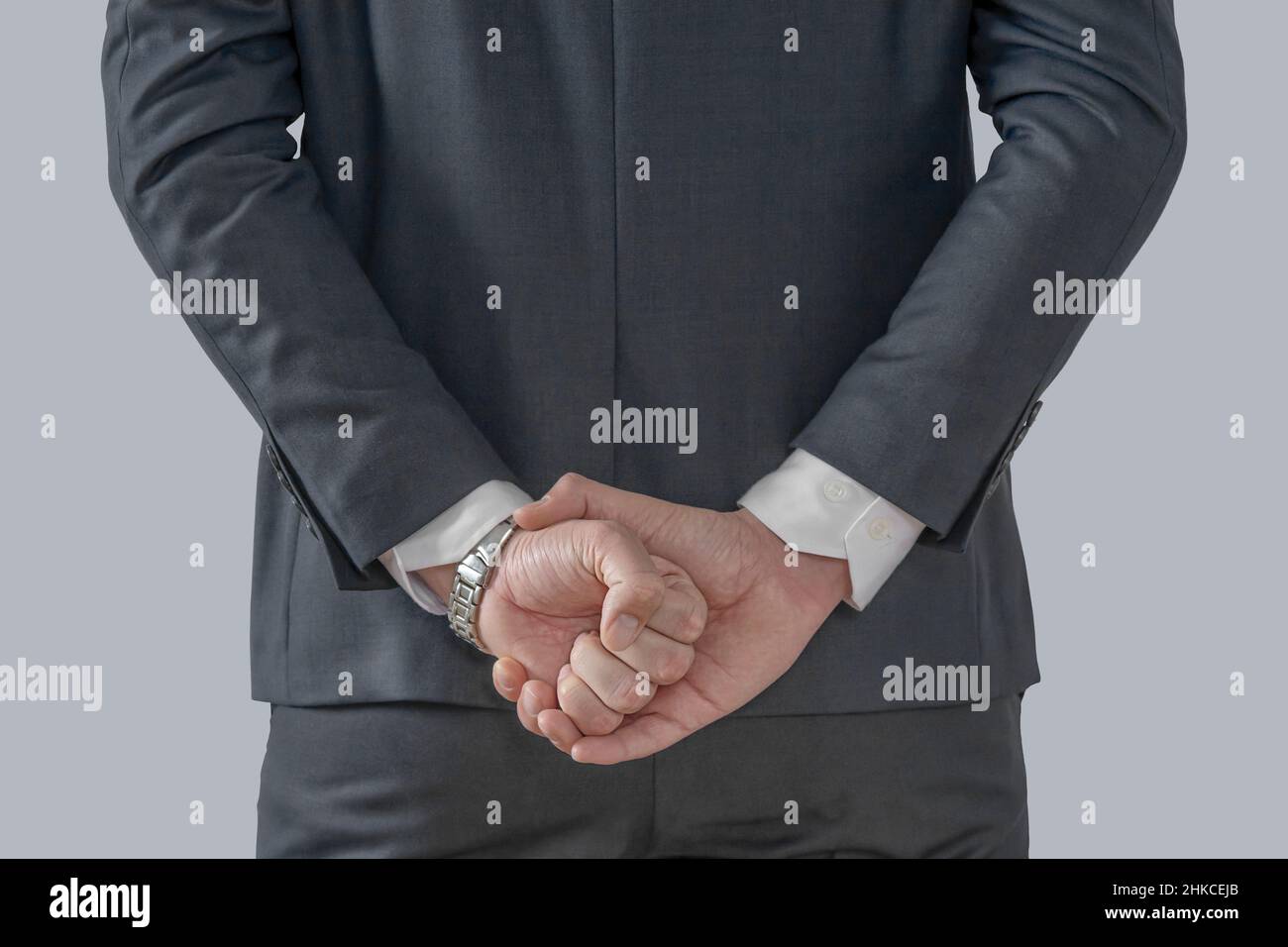 Businessman holding his hands behind his back Stock Photo - Alamy