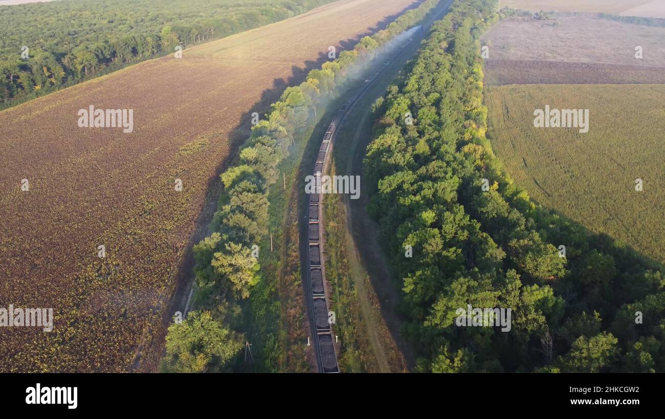 A long train with wagons travels by rail, a view from a drone on rail ...