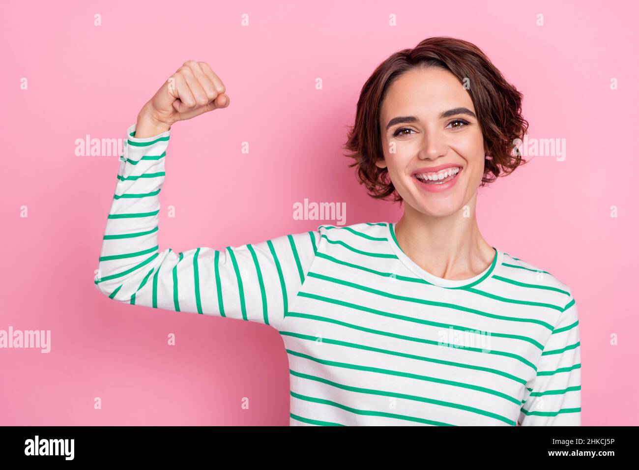 Portrait of attractive cheerful girl demonstrating muscles biceps ...