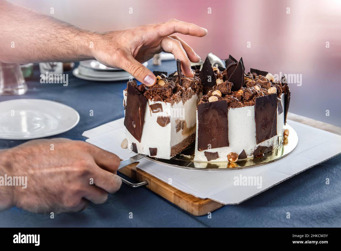 man's hands cut a chocolate cake. high layer cake prepared by a pastry ...