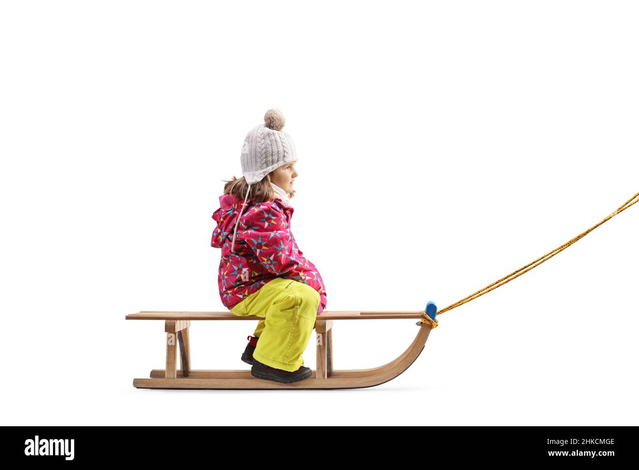 Full length profile shot of a little girl sitting on a sleigh isolated ...