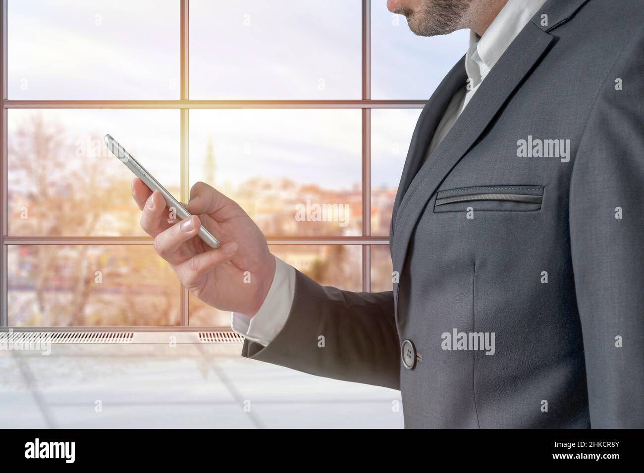 Male hands using modern mobile phone in the office with big window ...