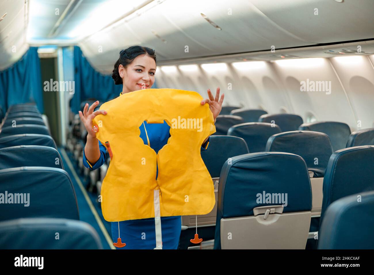 Female flight attendant with life vest standing in airplane Stock Photo ...