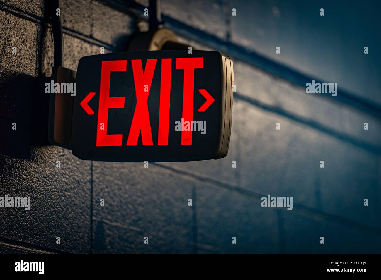glowing exit sign by night on black wall Stock Photo - Alamy