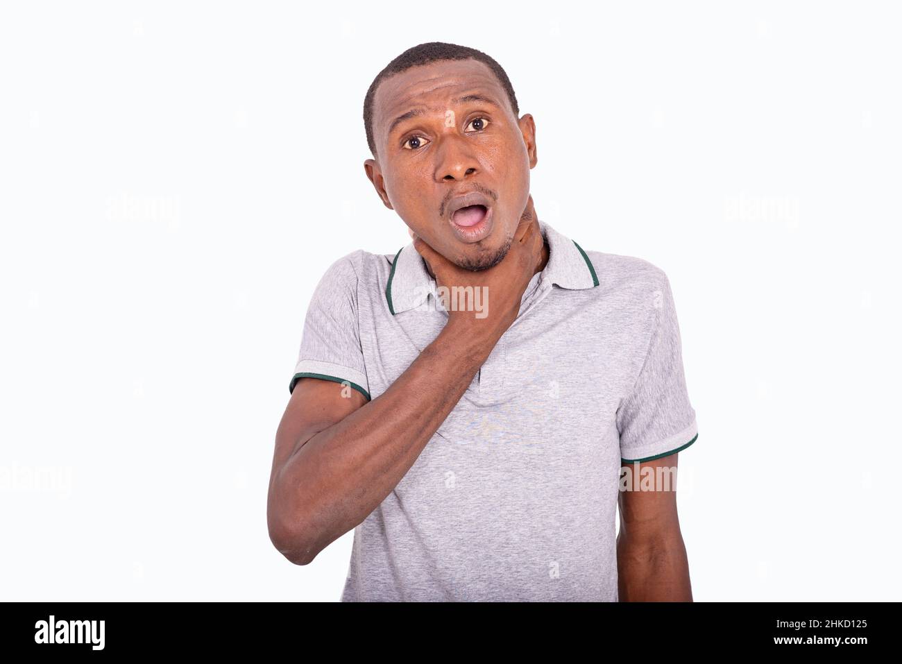 a young man in a gray t-shirt standing on a white background squeezing ...