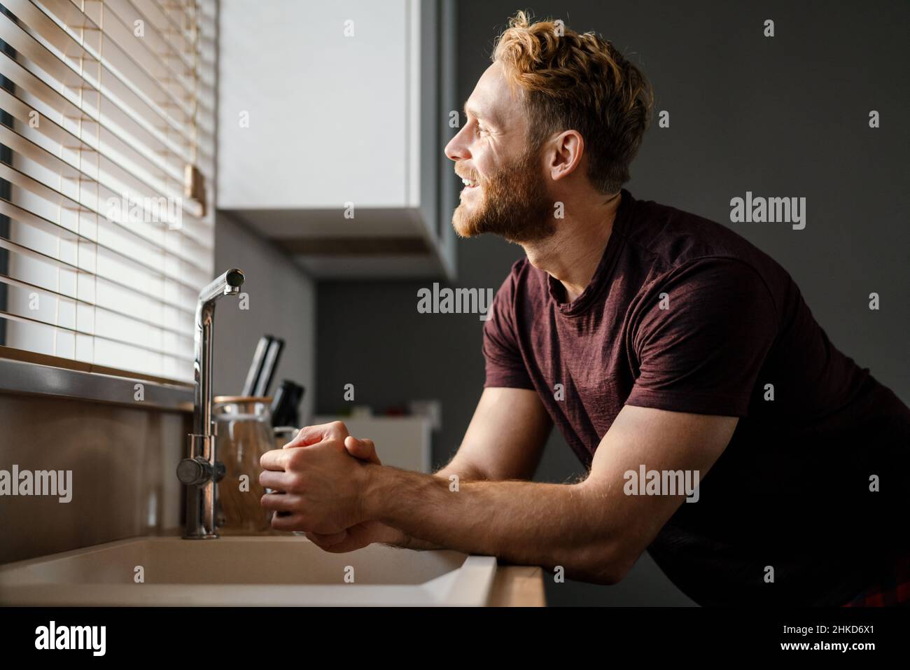 Attractive happy young man looking in the window while standing at the ...