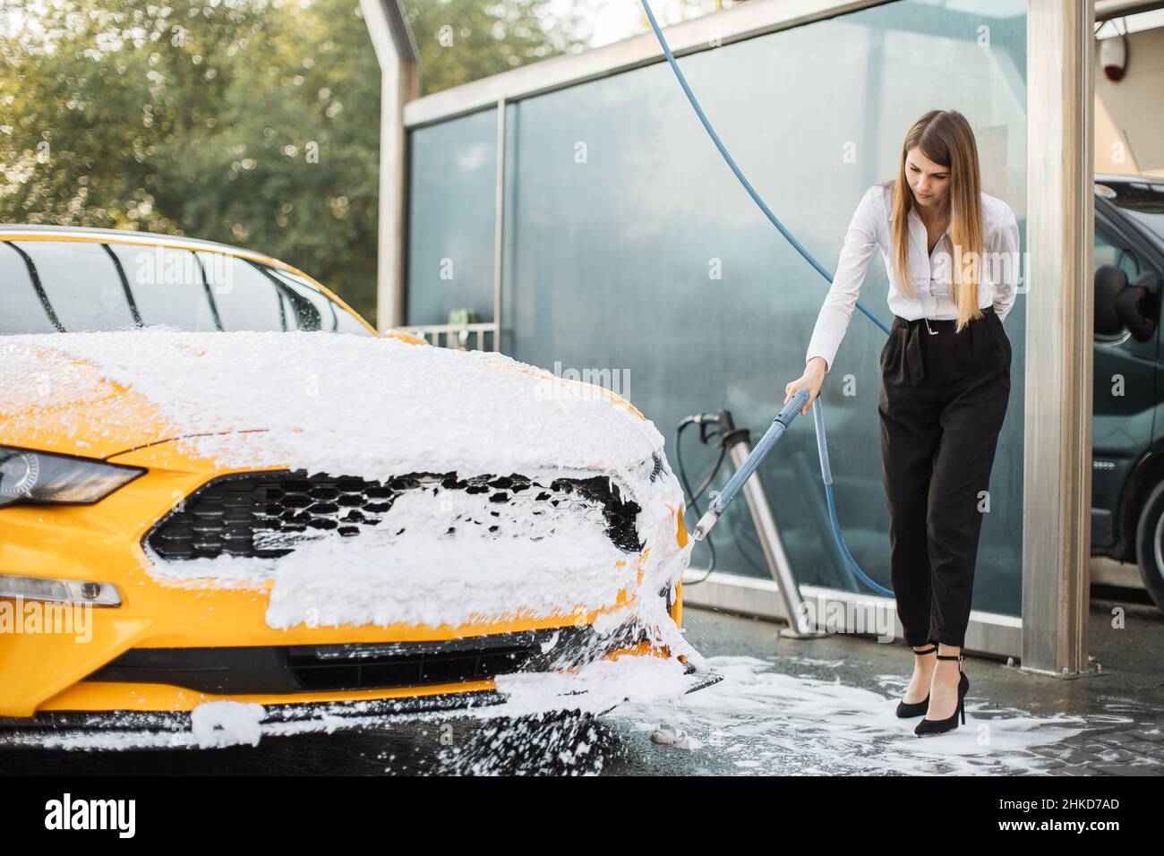 Attractive caucasian woman wear on business look washing his yellow car ...