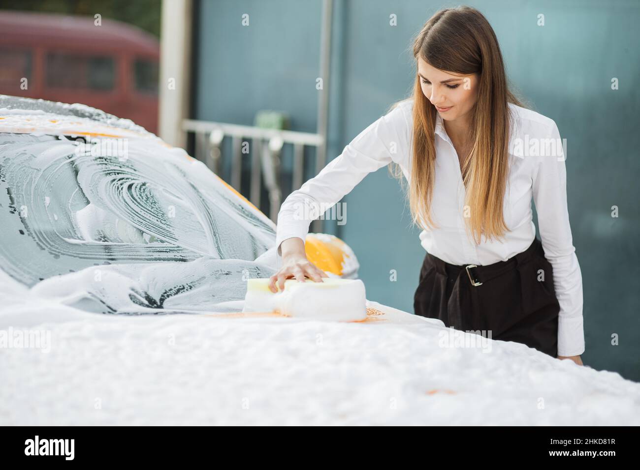 Confident stylish european businesswoman washing her modern luxury car ...