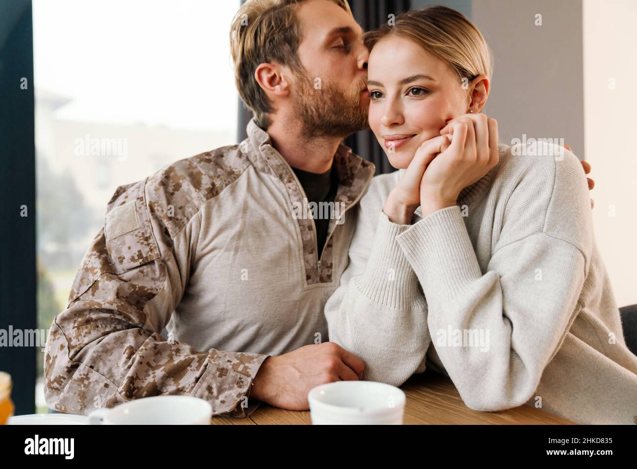 Beautiful happy young couple hugging and kissing while drinking coffee ...