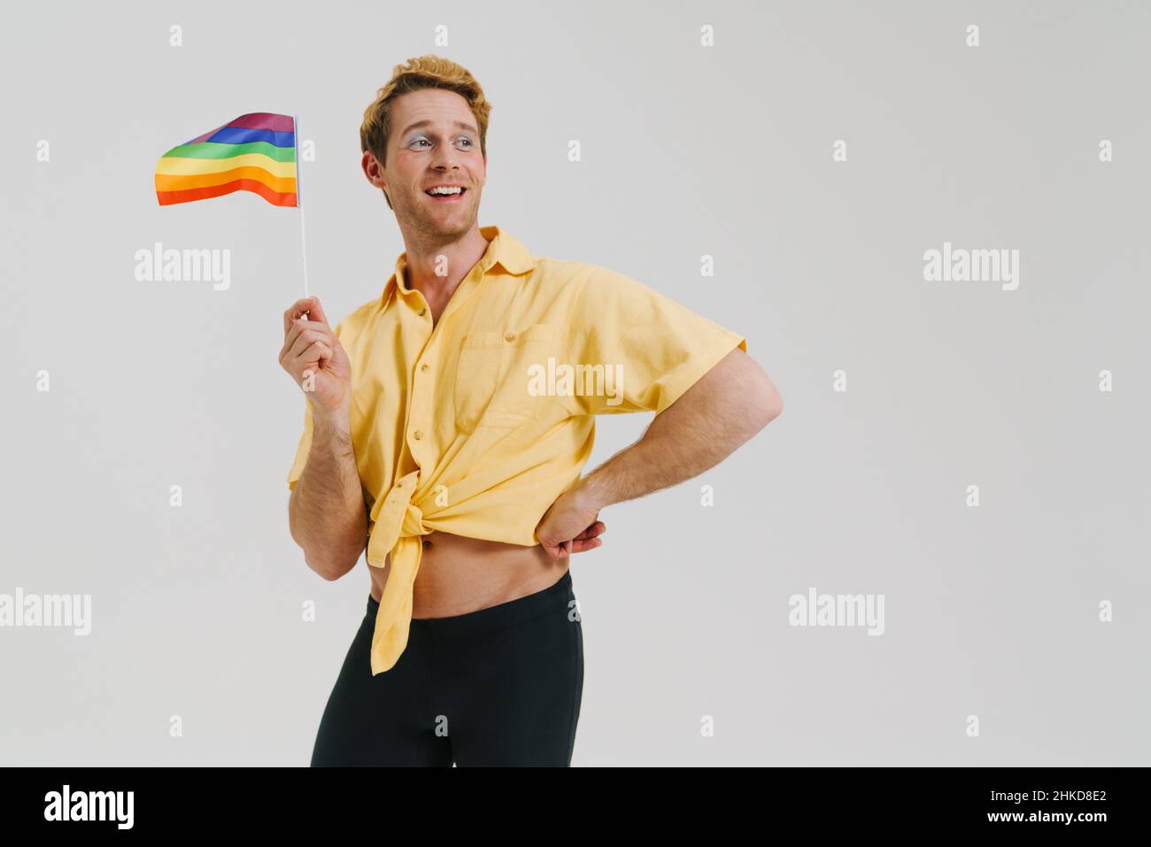 Ginger young man smiling and posing with rainbow flag isolated over ...