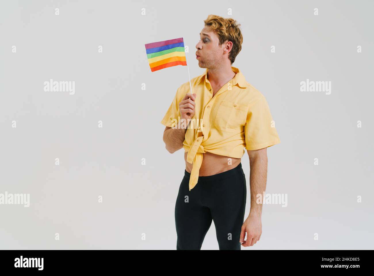 Ginger young man holding and blowing at rainbow flag isolated over ...