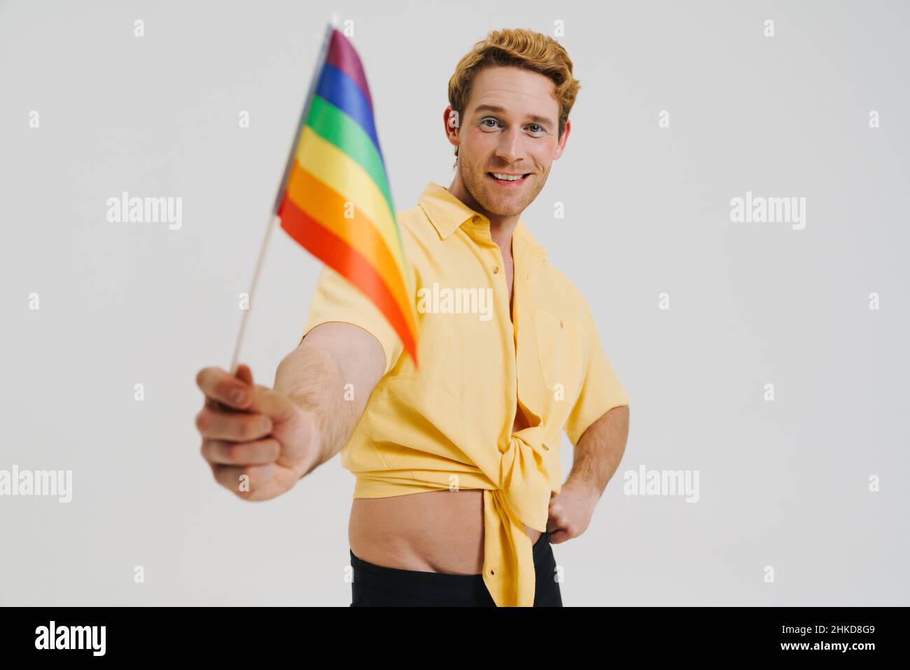 Ginger young man smiling and posing with rainbow flag isolated over ...