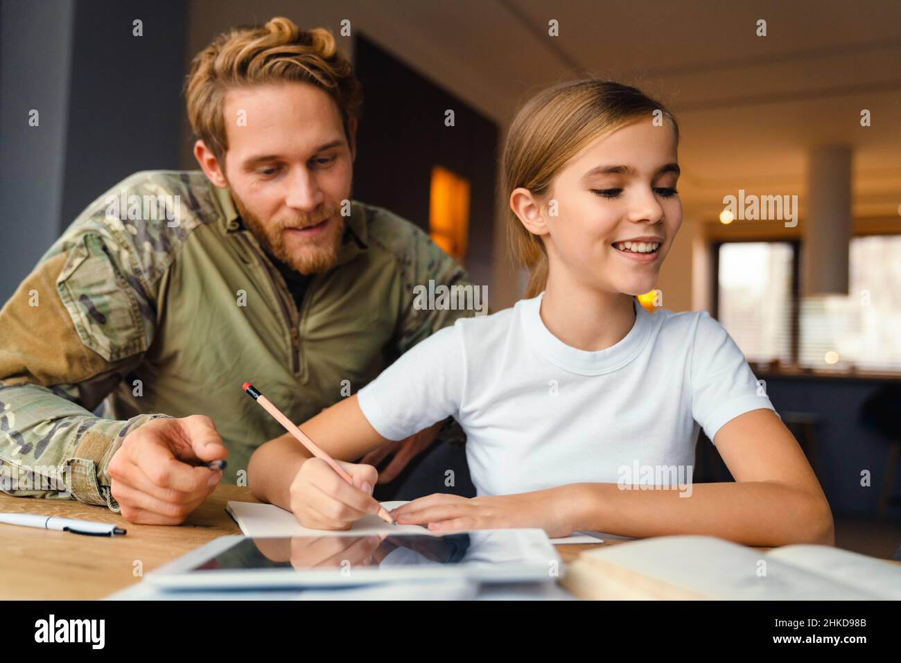 Masculine happy military man doing homework with her daughter at home ...