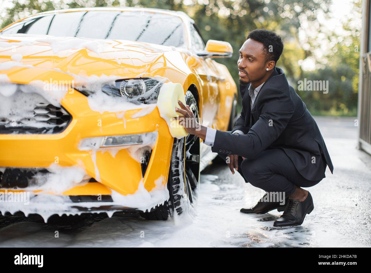 Car washing outdoors ar self wash service station. Handsome African ...