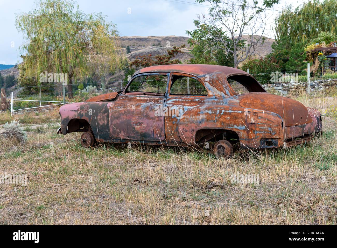 An old rusty car with no windows or tires left abandoned in a field ...