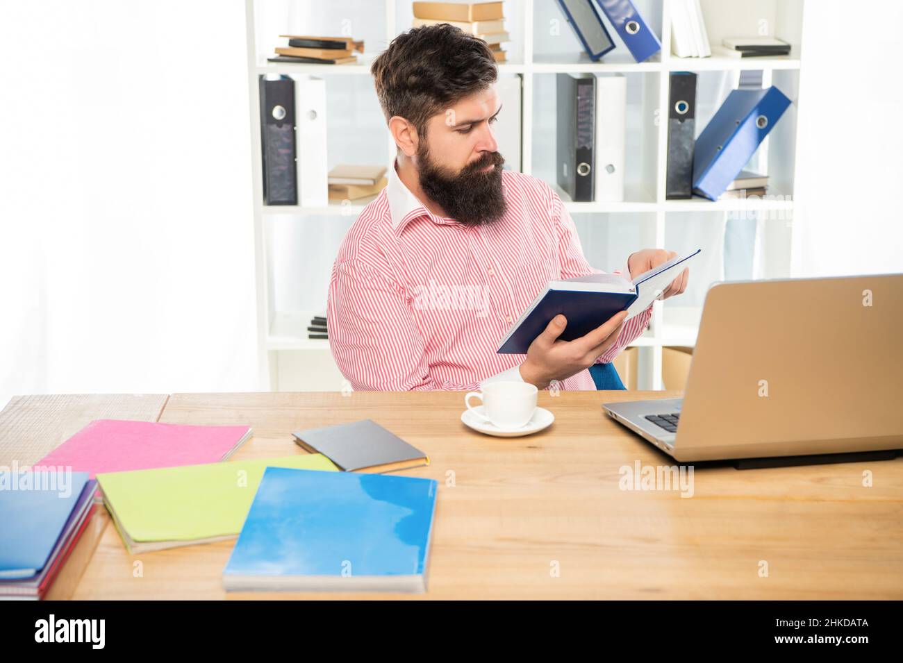 Serious professional man reading book at office desk Stock Photo - Alamy