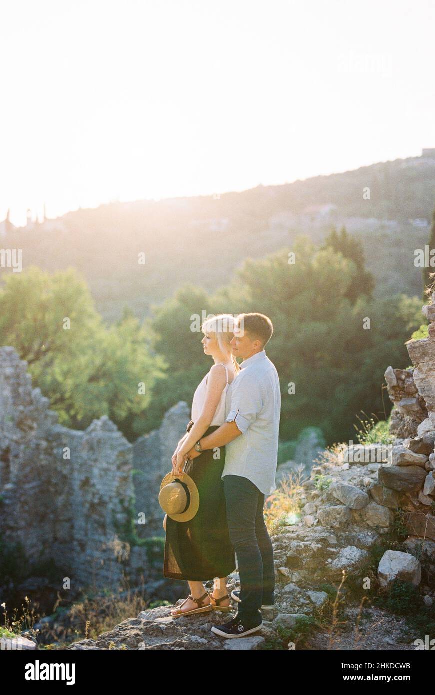 Man hugs woman from behind in the ruins of a castle. Side view Stock ...