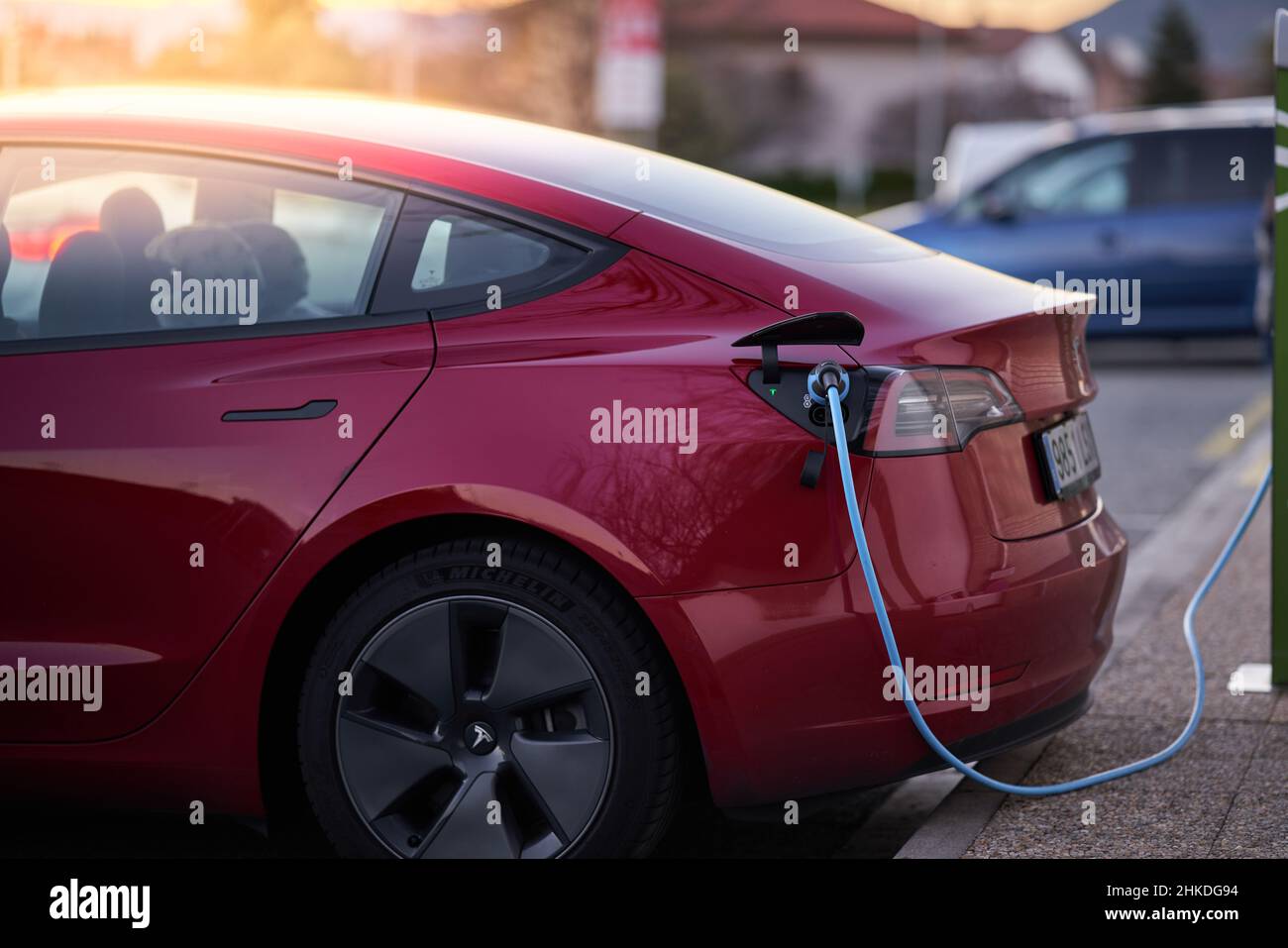 Modern red electric vehicle at the time of charging connected to ...