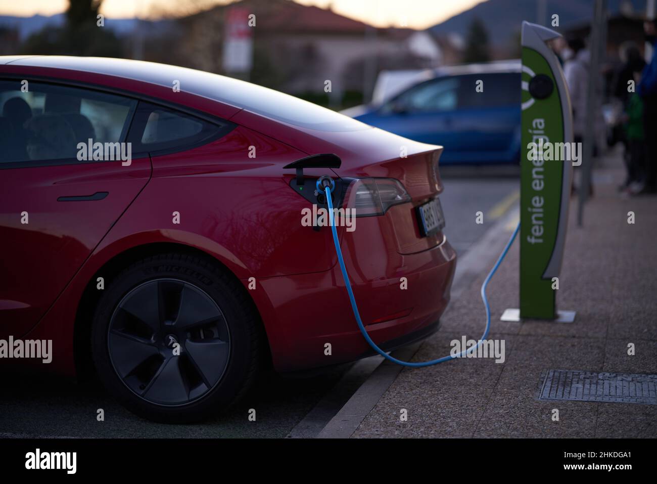 Modern red electric vehicle at the time of charging connected to ...