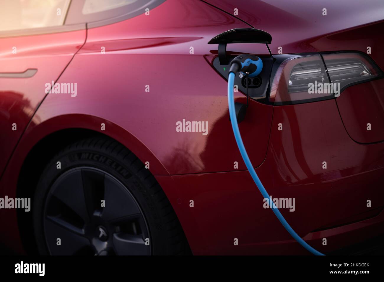 Modern red electric vehicle at the time of charging connected to ...