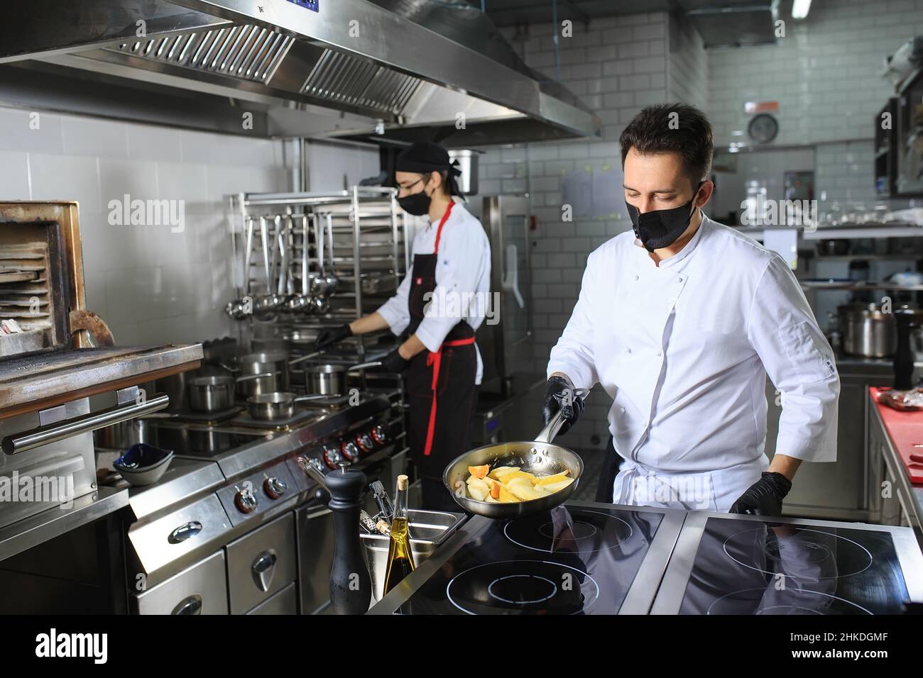 Young male chef flipping vegetables in wok at commercial kitchen Stock ...