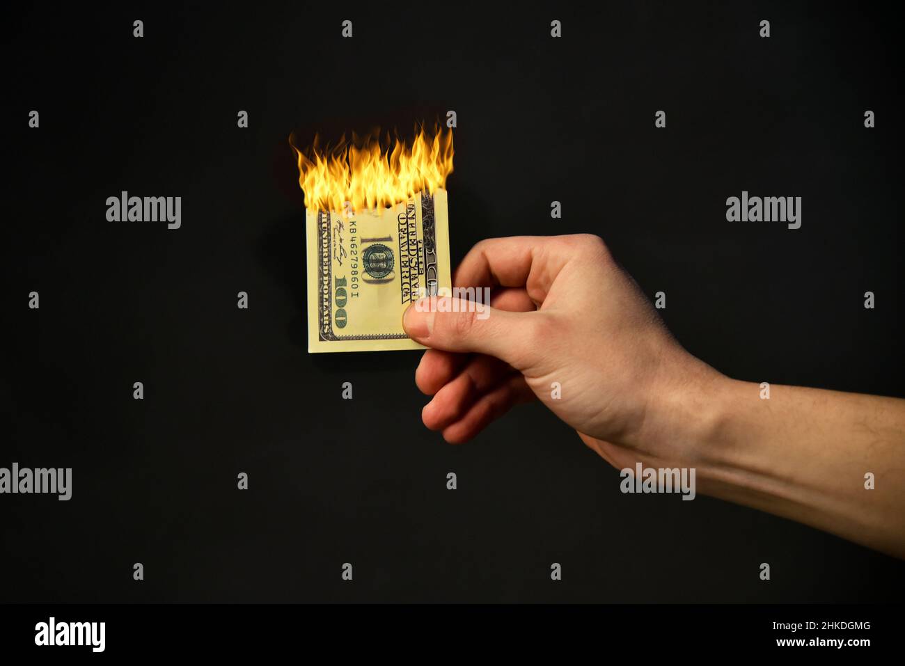 Burning dollar bill in flame hold in men hand against a black ...